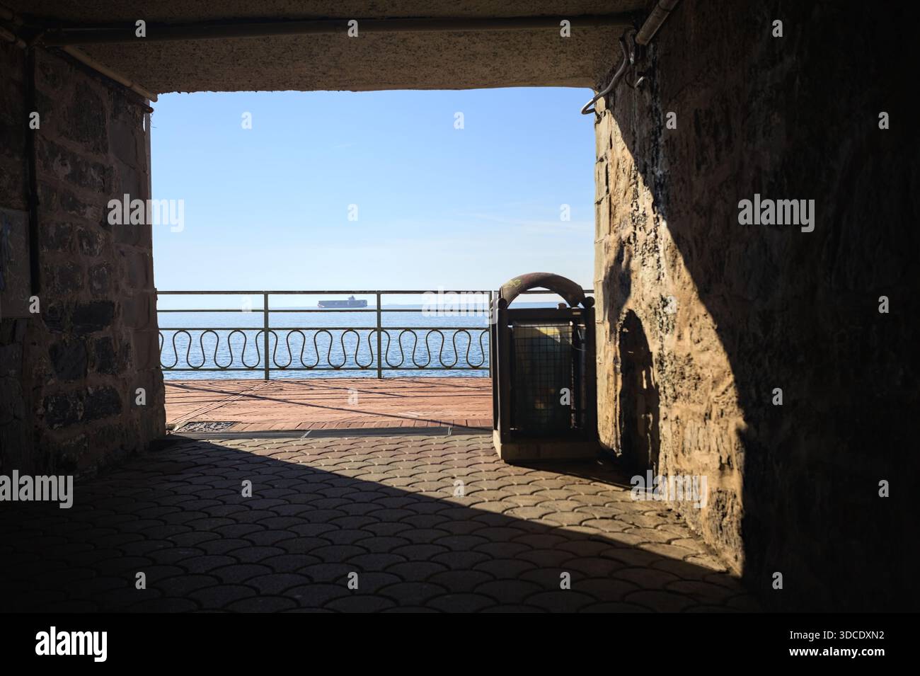Promenade on a cliff by the sea on a sunny day seen from a covered ...