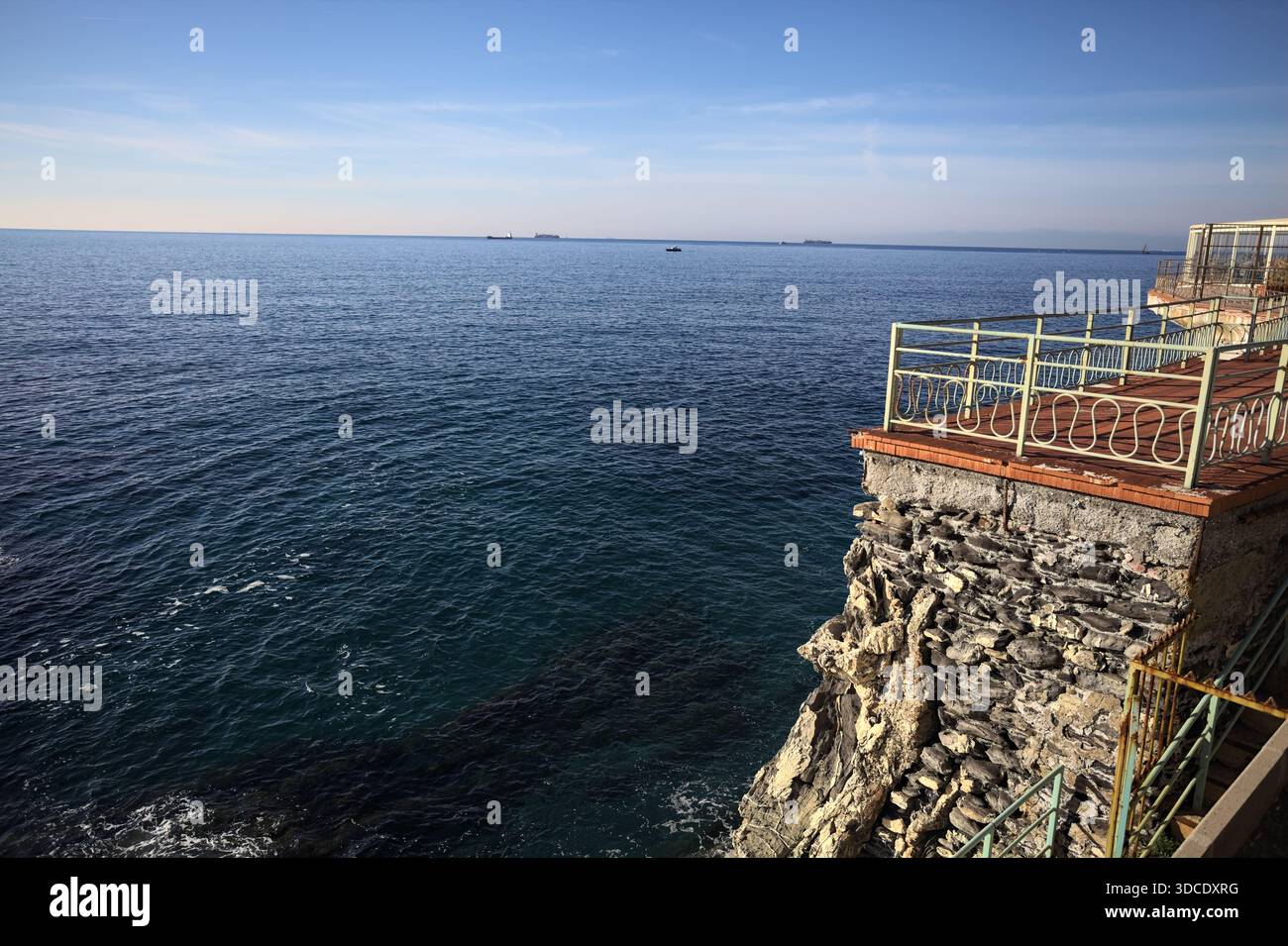 Promenade with an azure railing over a cliff with the sea down below ...