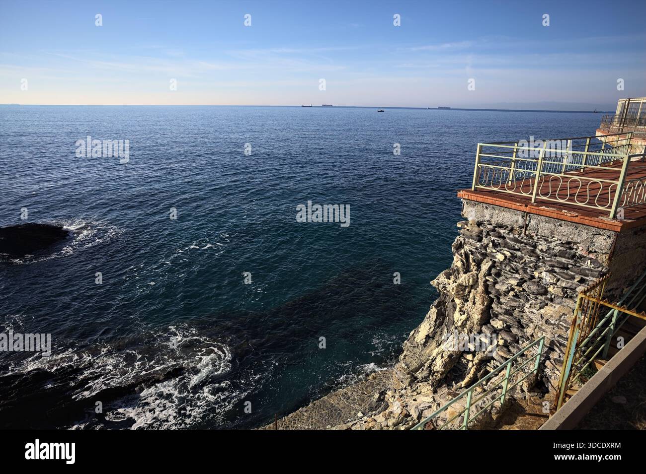 Promenade with an azure railing over a cliff with the sea down below ...