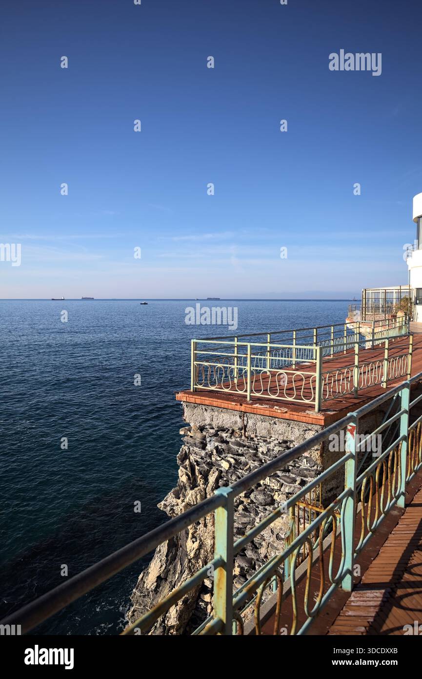 Promenade with an azure railing over a cliff with the sea down below ...