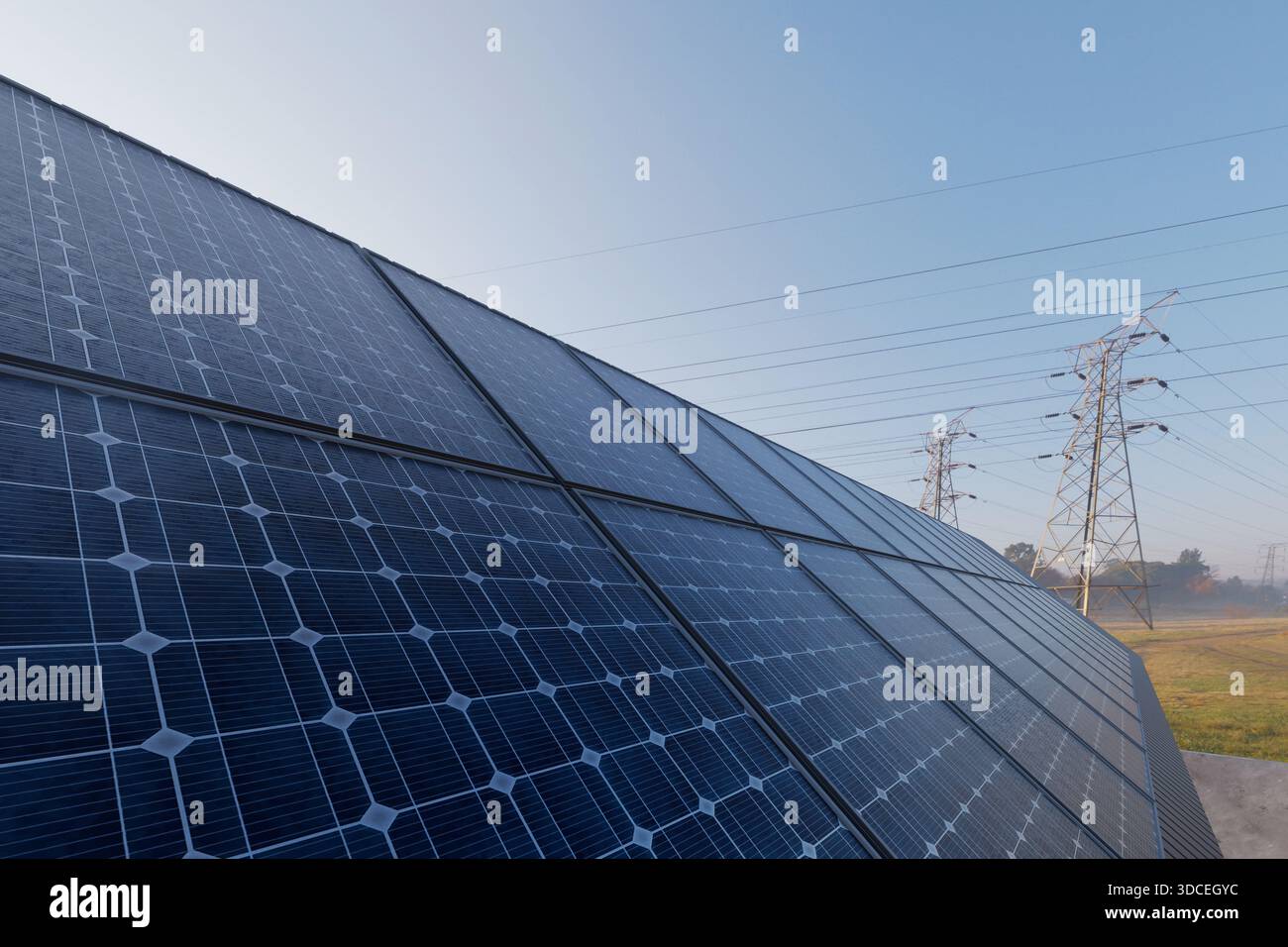 close-up of solar panels with power lines and transmission towers in ...