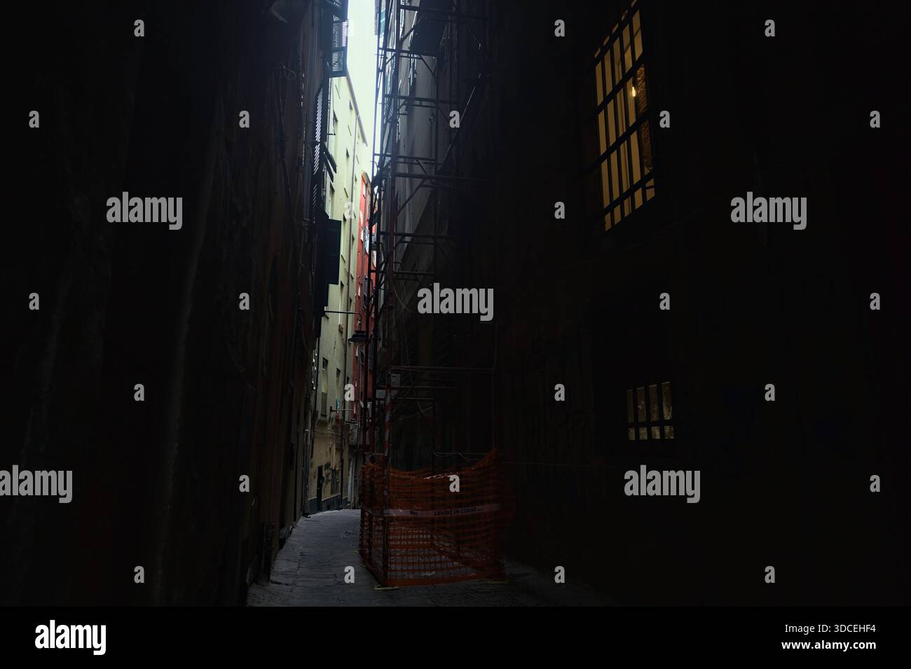 Alley in shade with a scaffolding in the middle of it and a clear sky ...
