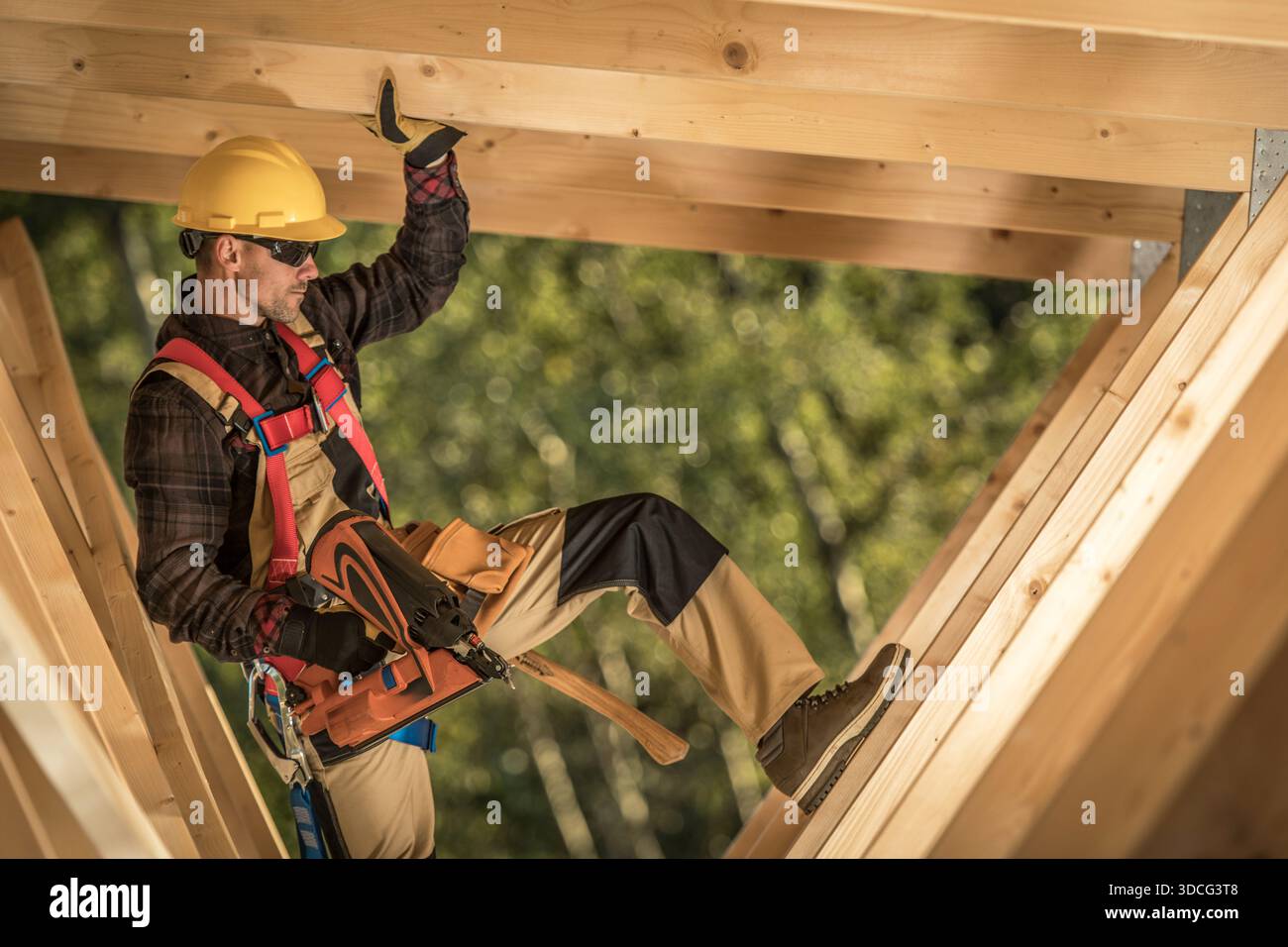A construction worker uses safety gear while climbing wooden beams to ...