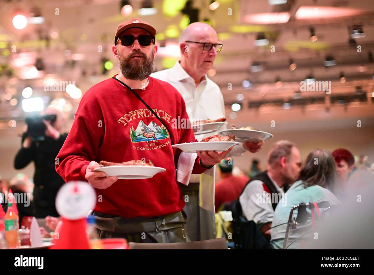 22 December 2025, Berlin: MC Fitti (front), rapper, serves food in ...