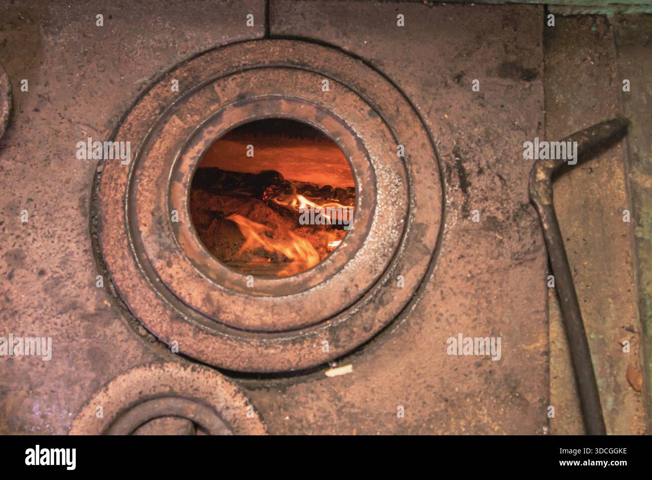 Old rural wood fired stove with open firebox burning logs inside cast ...