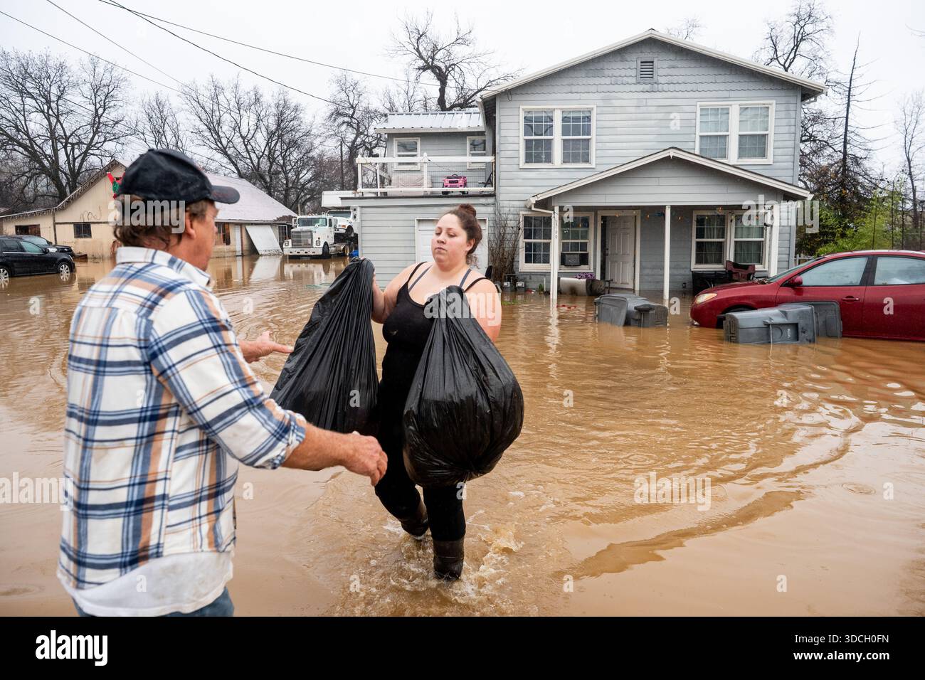 Cassidy Whitaker carries belongings from her flooded home on Monday ...