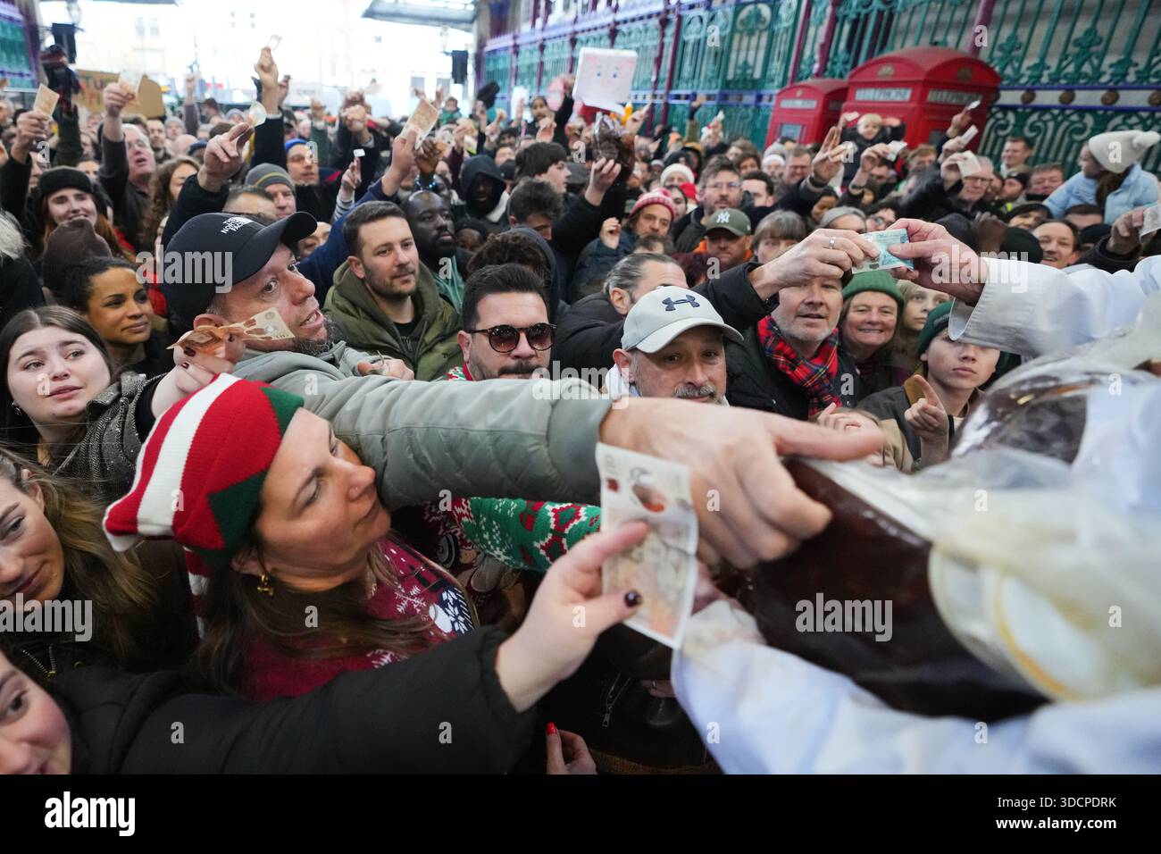 People hold out money during the annual Christmas Eve meat auction at ...