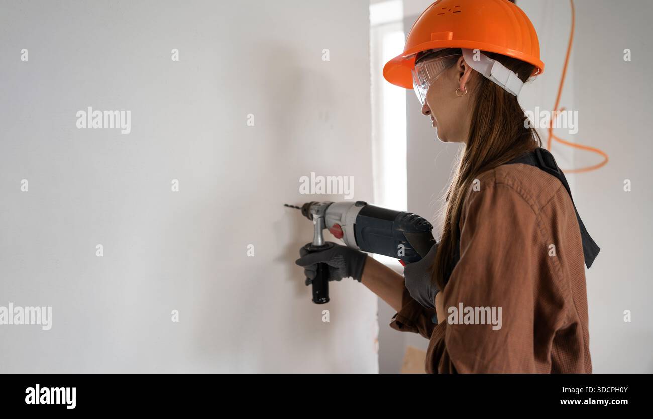 Female construction worker using hammer drill. Builder woman with ...