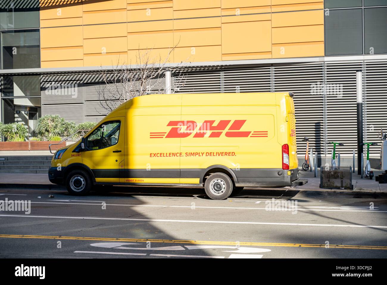 DHL delivery van parked on city street in front of modern office ...