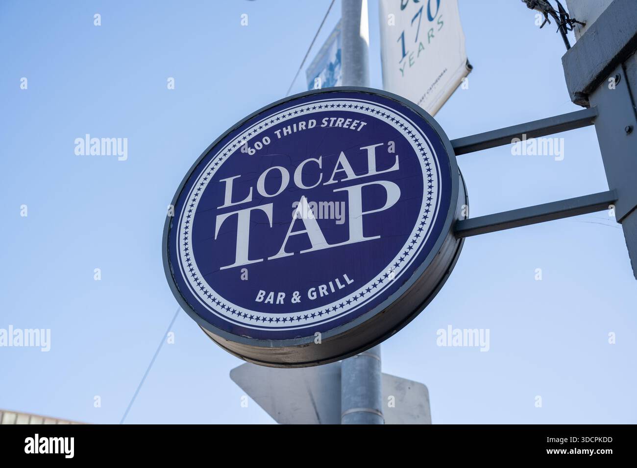 Round hanging sign for Local Tap Bar & Grill on city street corner ...