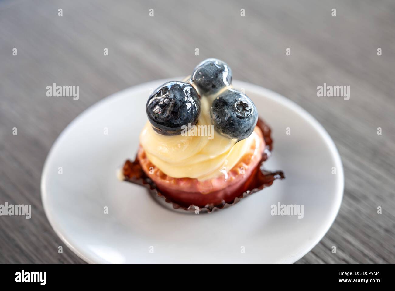 Pastry dessert topped with creamy filling and fresh blueberries, styled ...