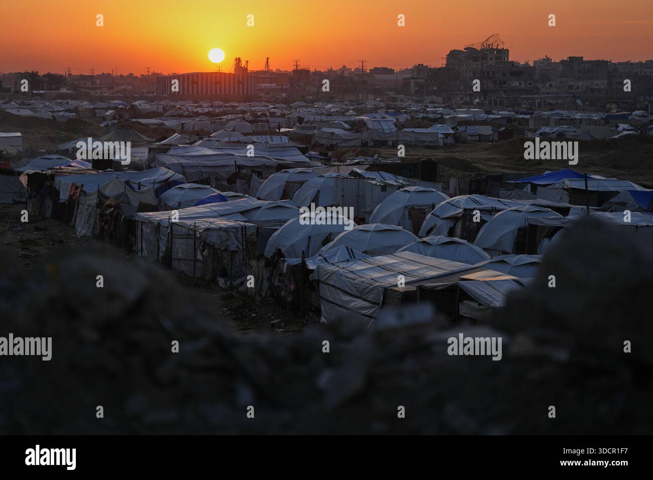 The sun sets behind a makeshift tent camp for displaced Palestinians ...