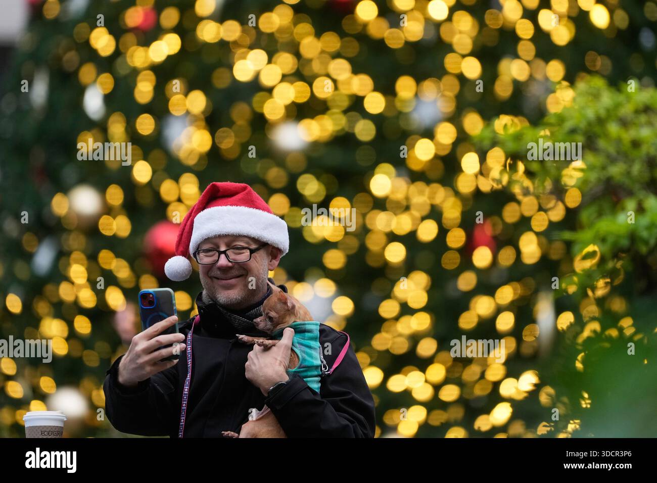 Christian Jennert holds his dog, Spatz, while looking at his phone in ...