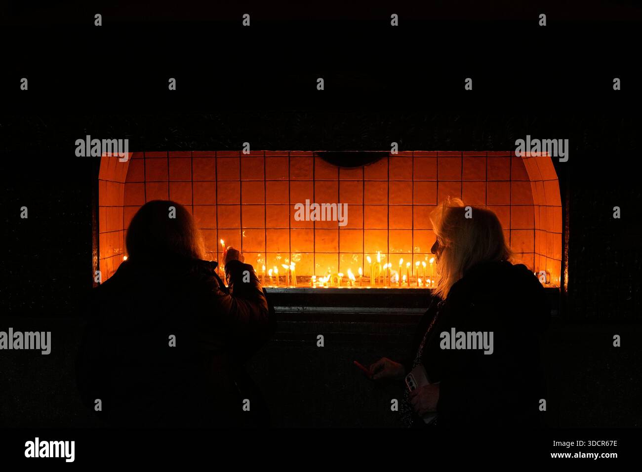 Two women light candles during a Catholic Christmas Eve mass in St ...