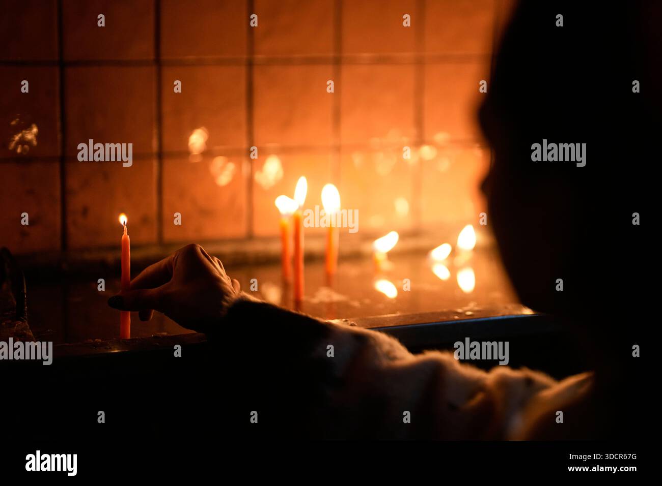 A women lights a candle during a Catholic Christmas Eve mass in St ...