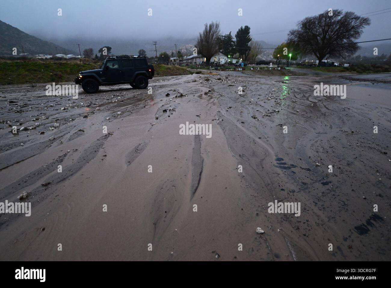 A car drives over mud along California State Route 138 after flooding ...