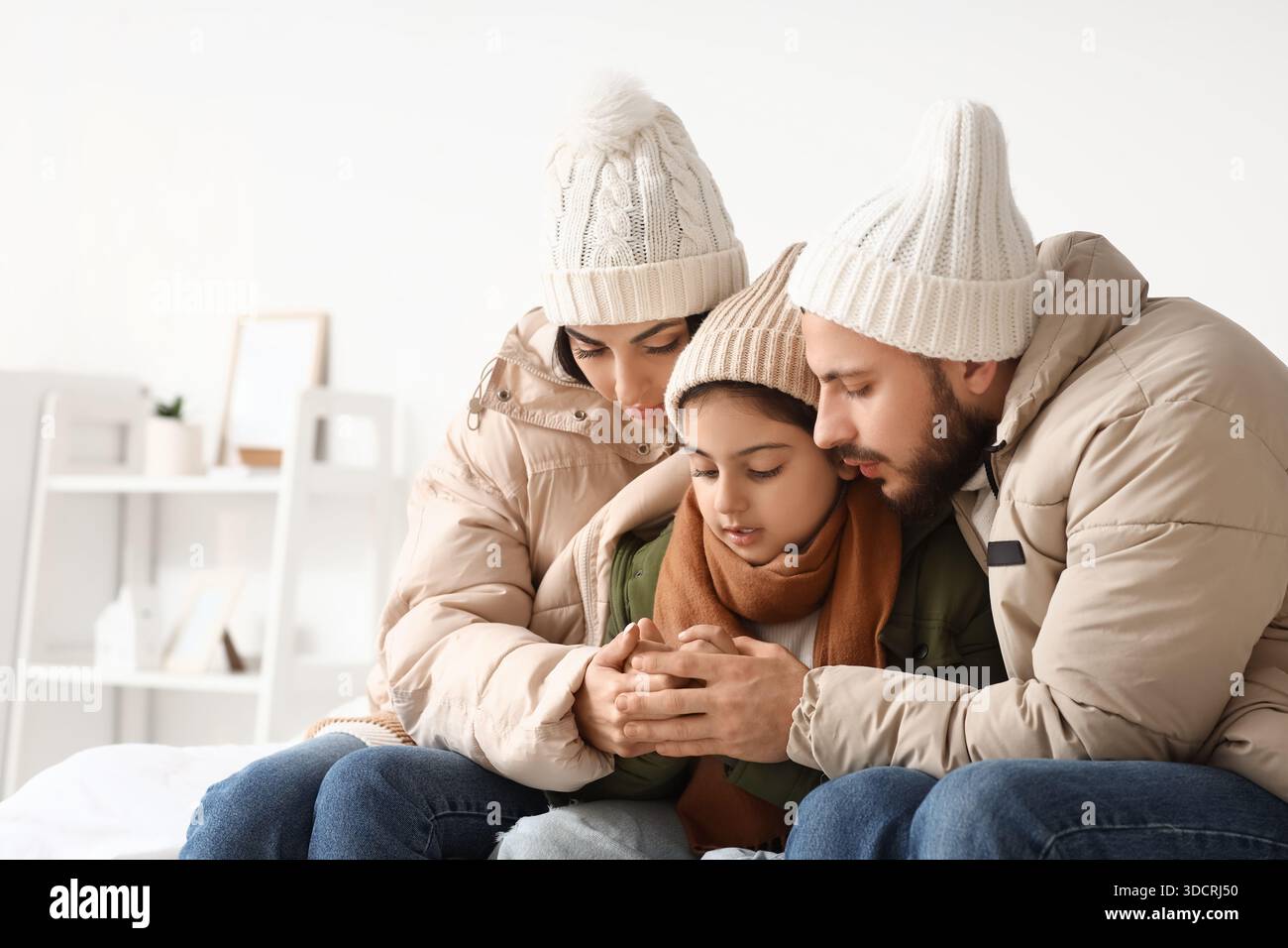 Frozen family with winter clothes and lack of heating hugging in ...