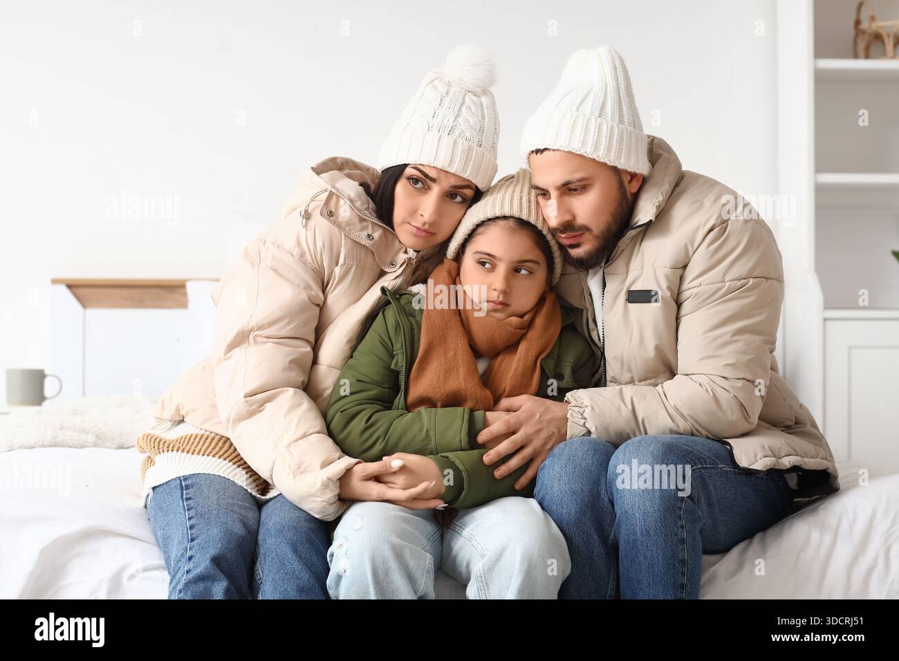 Frozen family with winter clothes and lack of heating hugging in ...