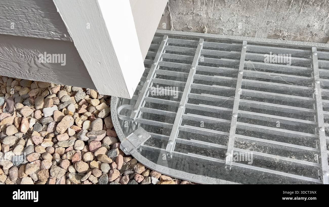 Metal window grate beside siding and gravel Stock Photo - Alamy