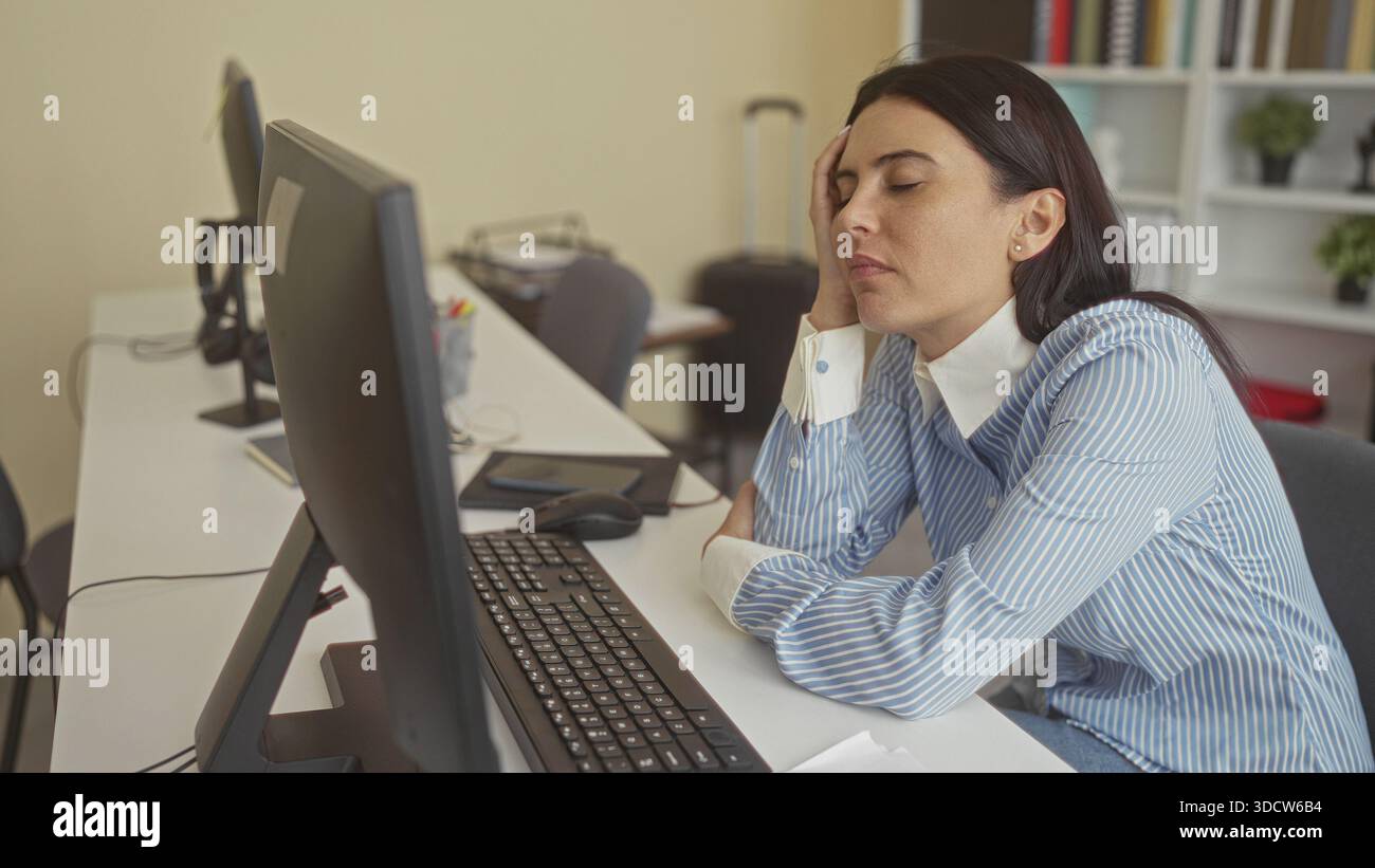 Woman resting head on desk at computer monitor and keyboard, hand to ...