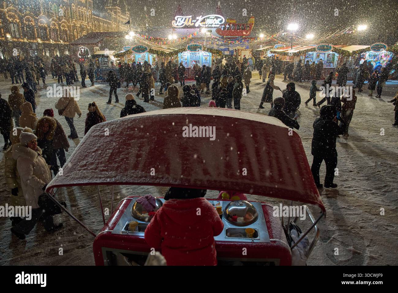 People walk under snowfall at the Christmas fair decorated for ...