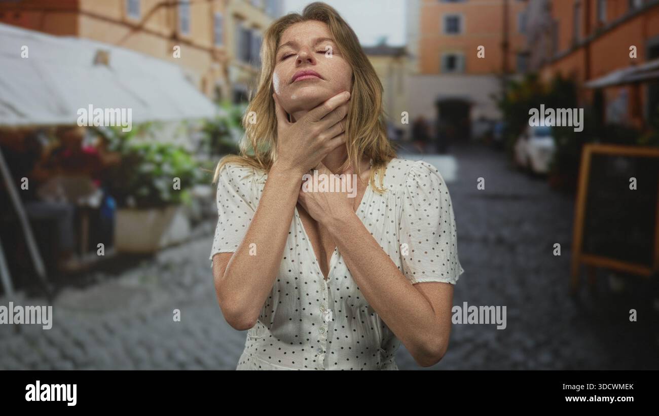 Woman grasping neck with both hands on street, head tilted back and ...