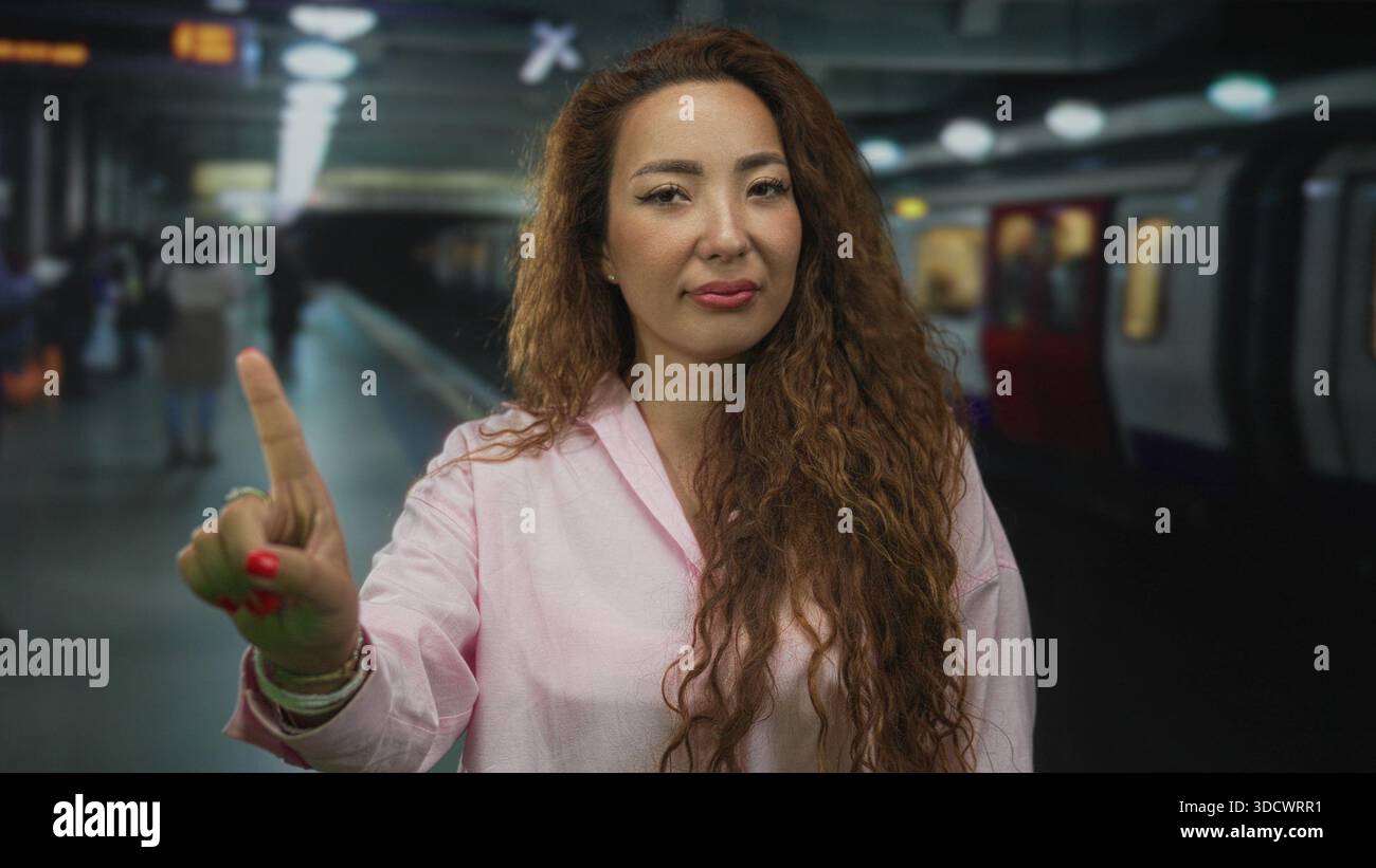 Woman points finger at platform edge inside a train station building ...