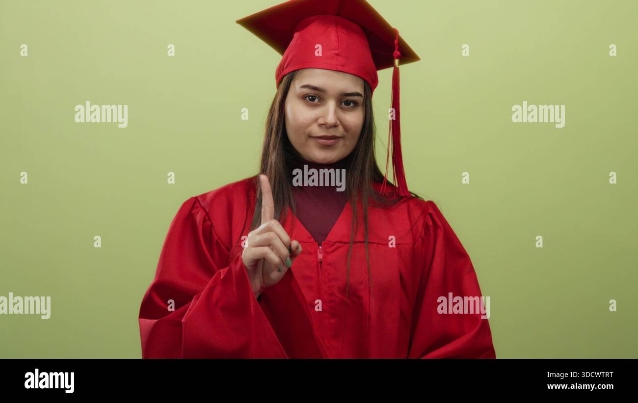 Woman in red graduation gown gestures no against yellow background ...