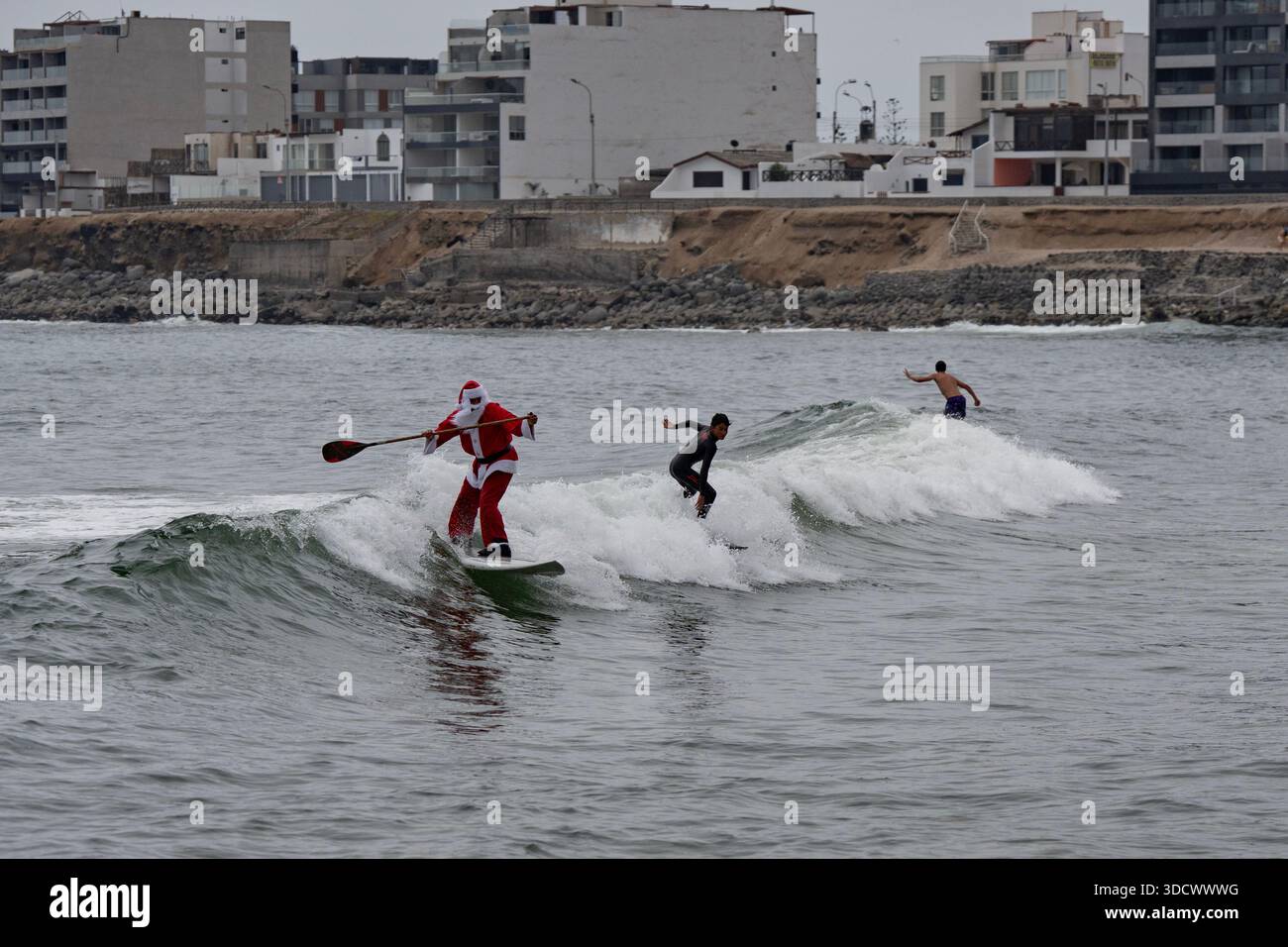 Daniel Alvistur, dressed as Santa Claus, paddleboards in San Bartolo ...