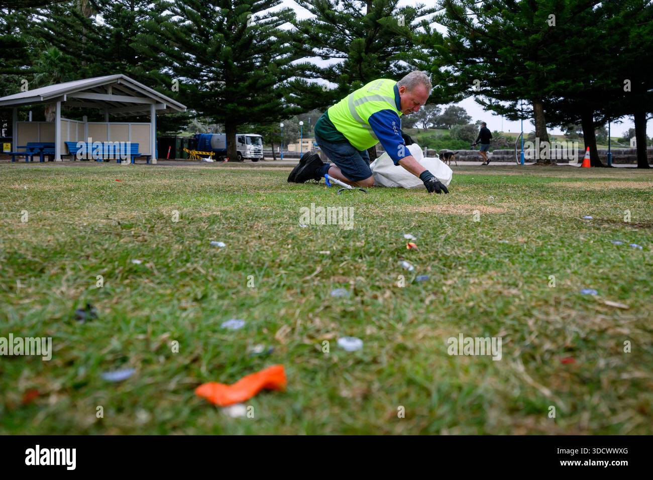A worker picks up the broken glass left on the lawn after the Christmas ...