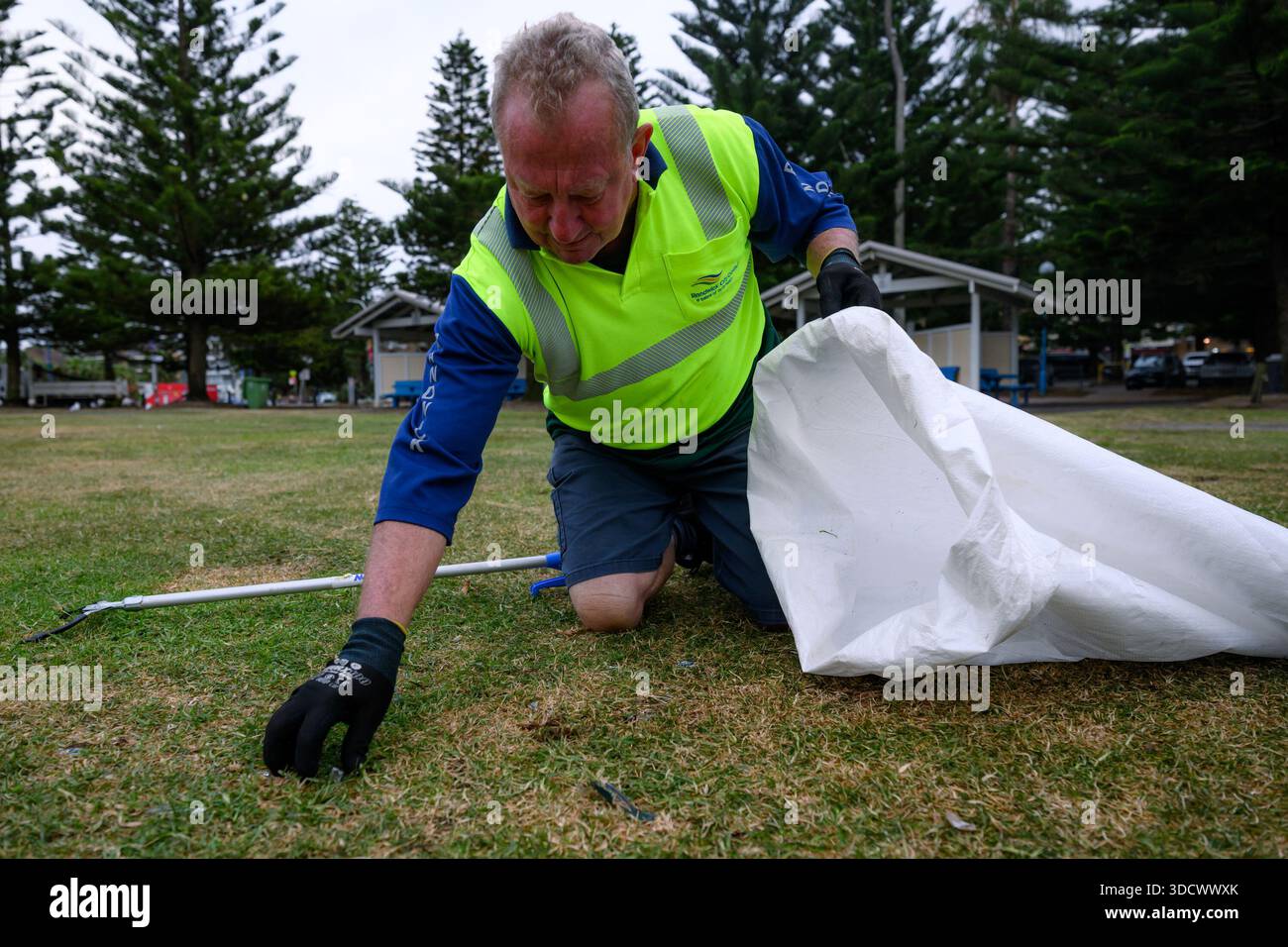 A worker picks up the broken glass left on the lawn after the Christmas ...