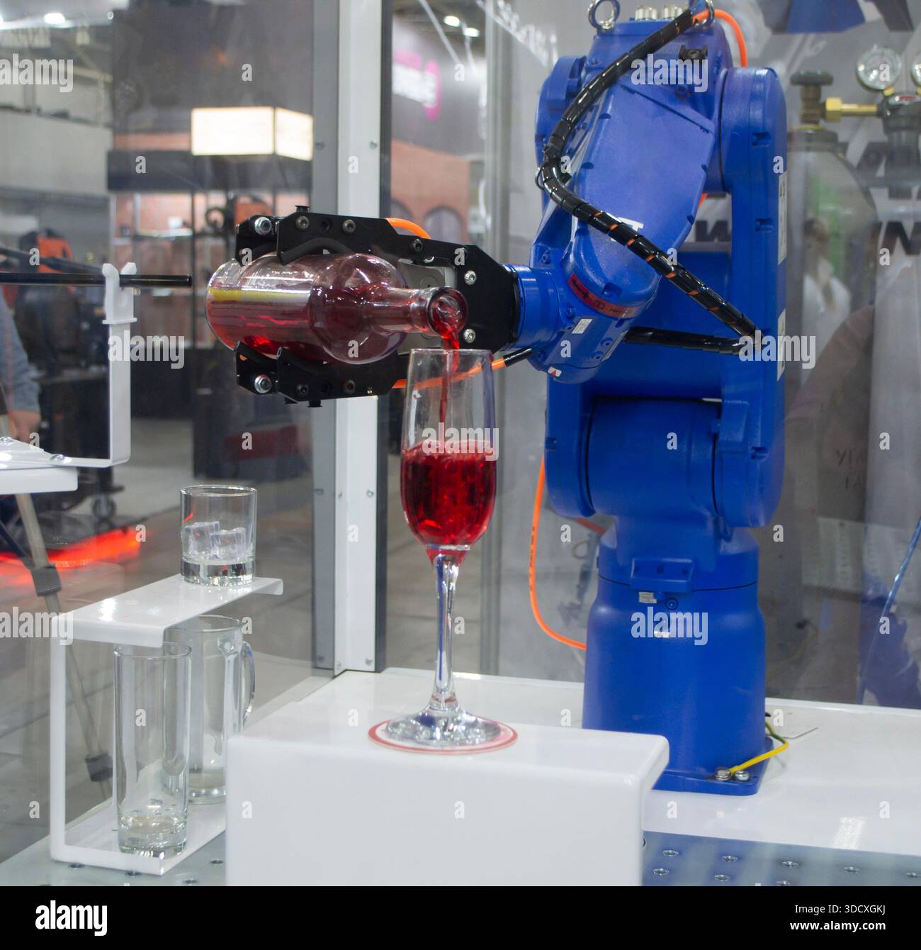 Robotic manipulators. Robot pouring liquid drink from bottle into glass ...