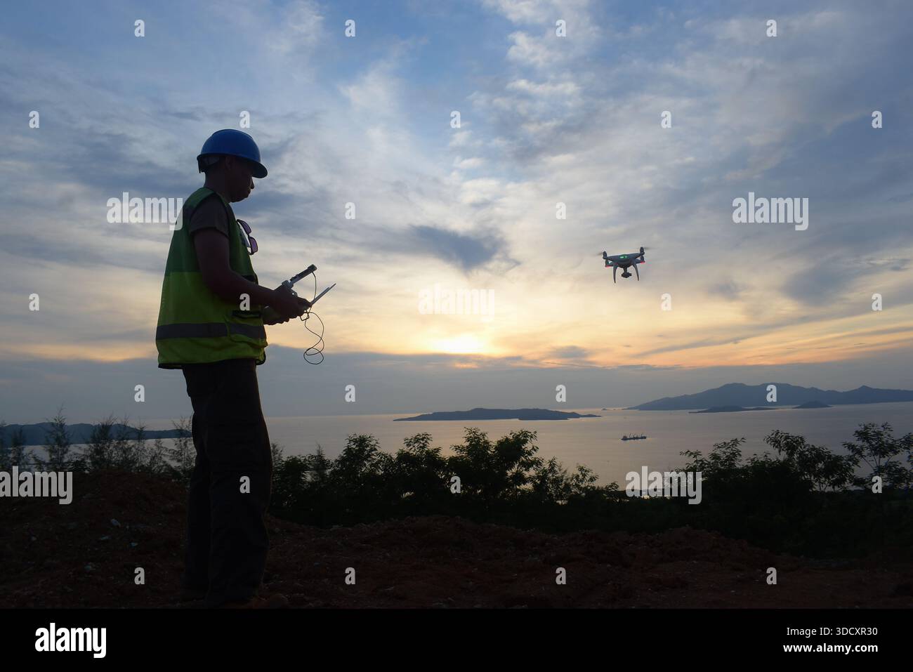 Field engineer flying a drone surveying the landscape. Sunset ...