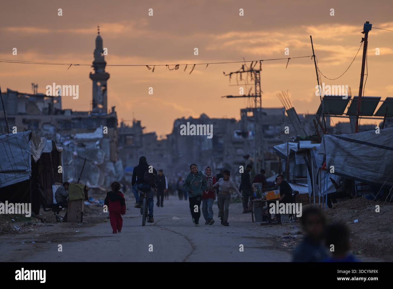 Palestinian youth walk along a tent camp for displaced people as the ...