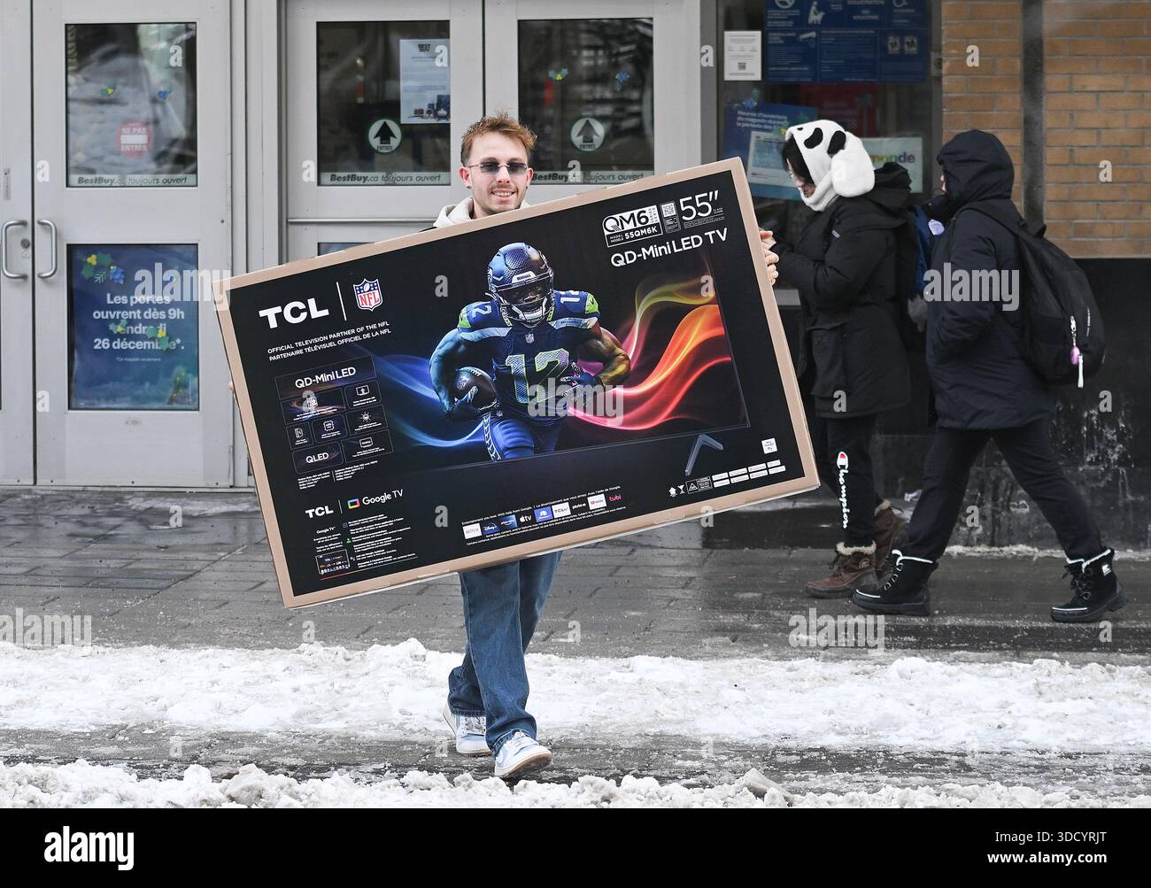 A man carries a large screen television from a Best Buy store on Boxing ...