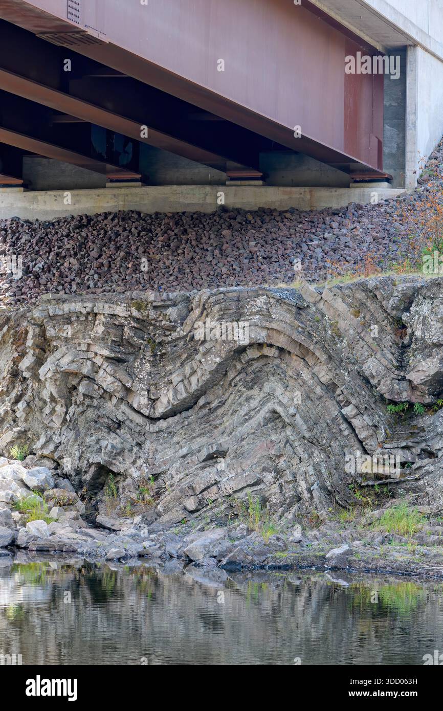 A geologic fold in sedimentary rock under a bridge over a brook. Many ...