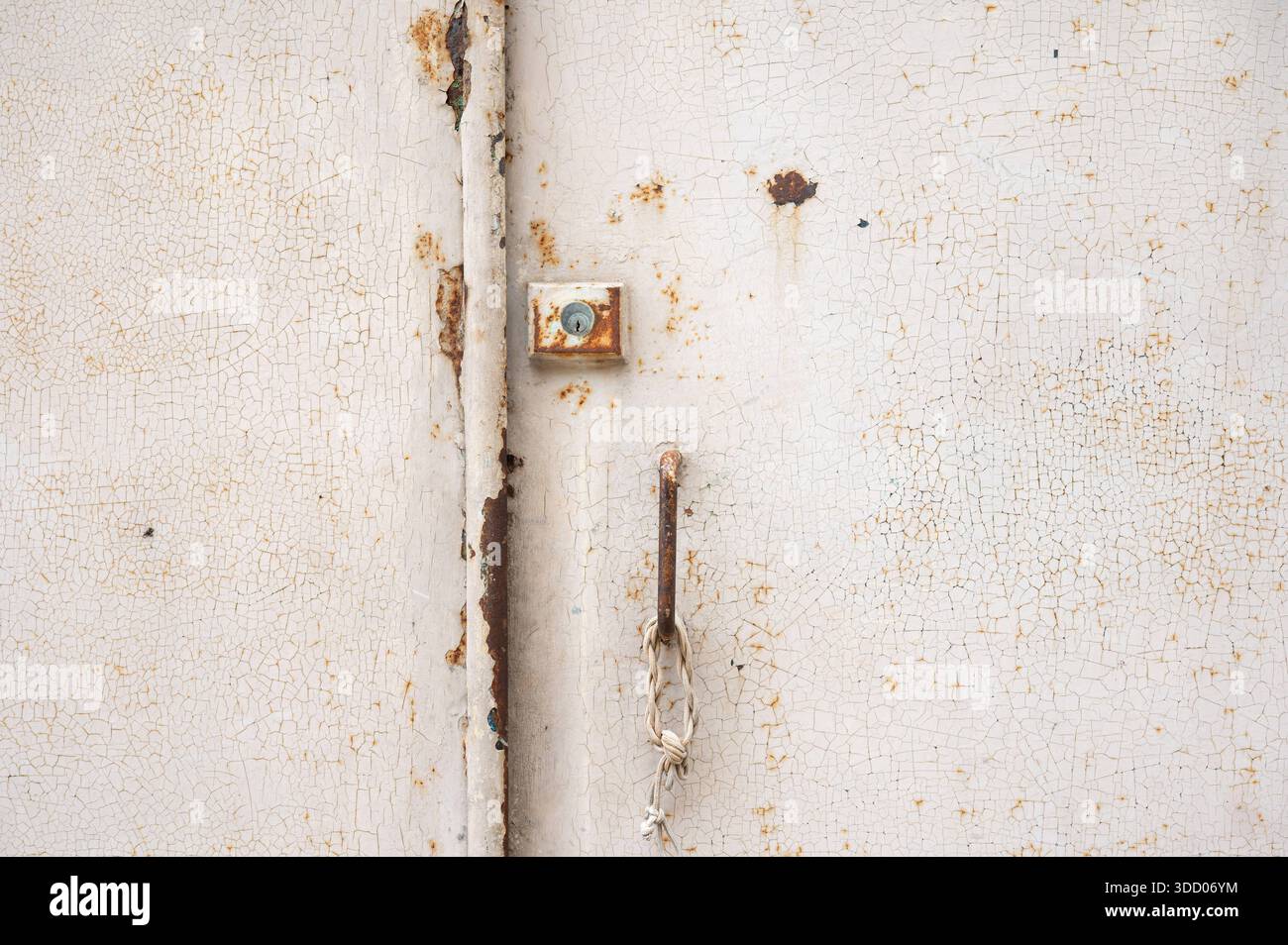 Rusted metal door with peeling off-white paint, creating a rough and ...