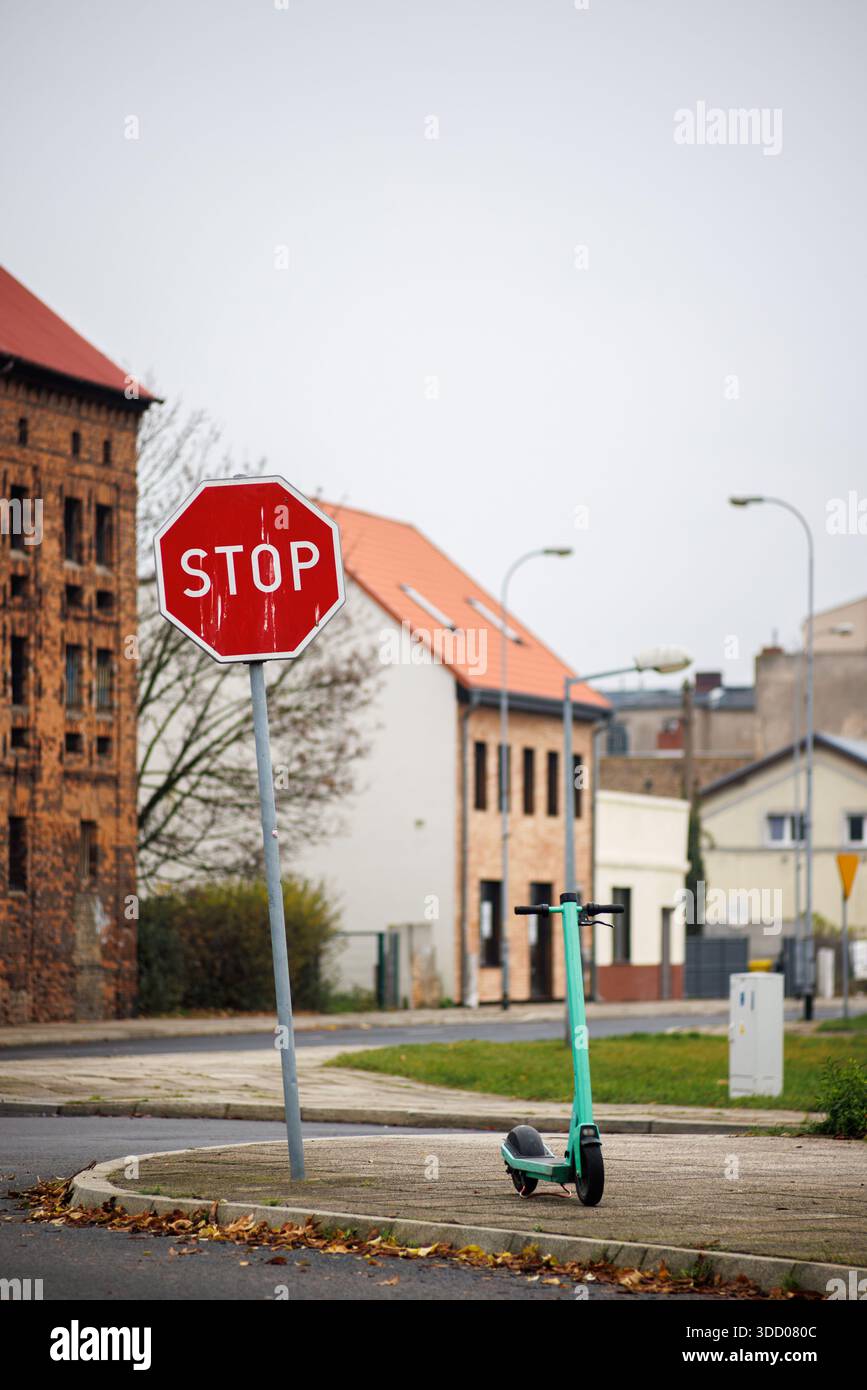 A tilted red STOP sign and an electric scooter against the backdrop of ...
