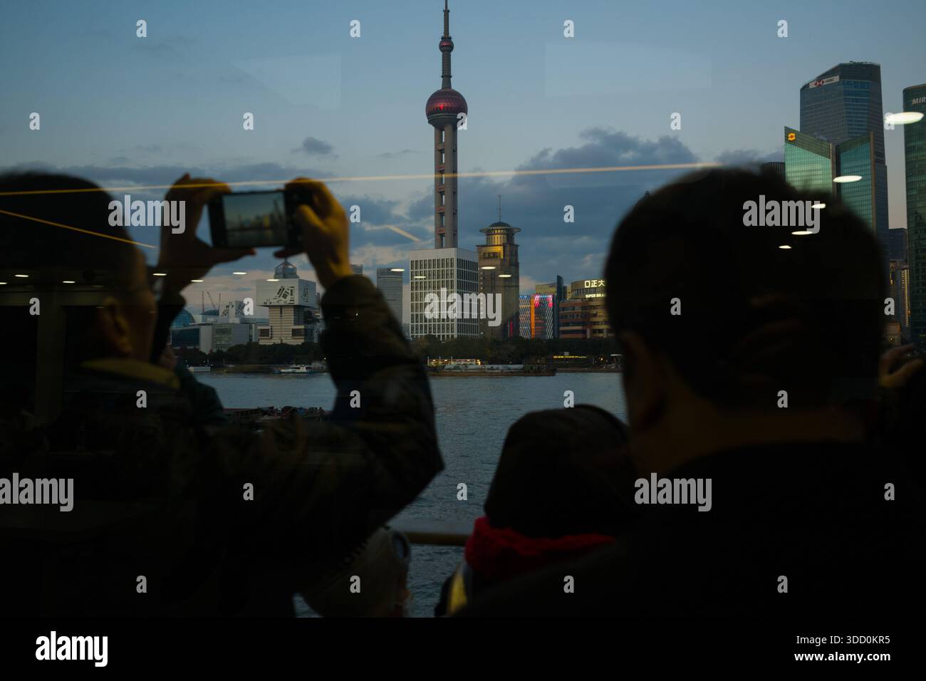 At sunset, people take photos of Pudong riverside from a ferry boat on ...