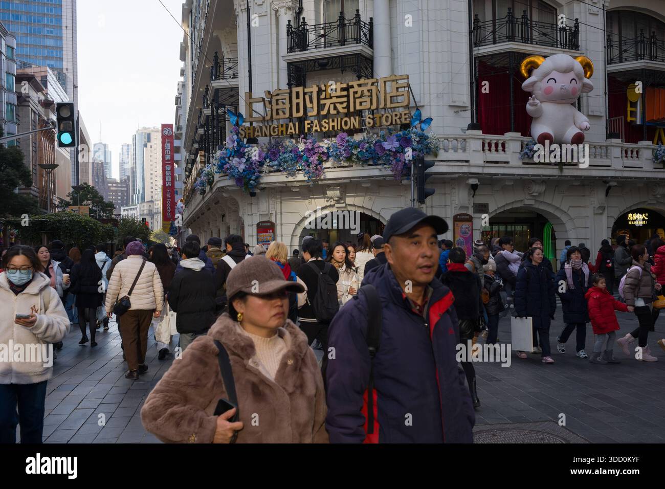 People walk across a storefront on the Walking Street of Nanjing Road ...