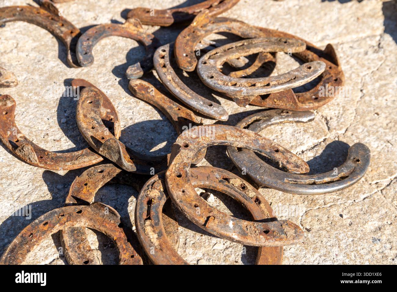 A collection of old, rusty horseshoes scattered on a rough stone ...