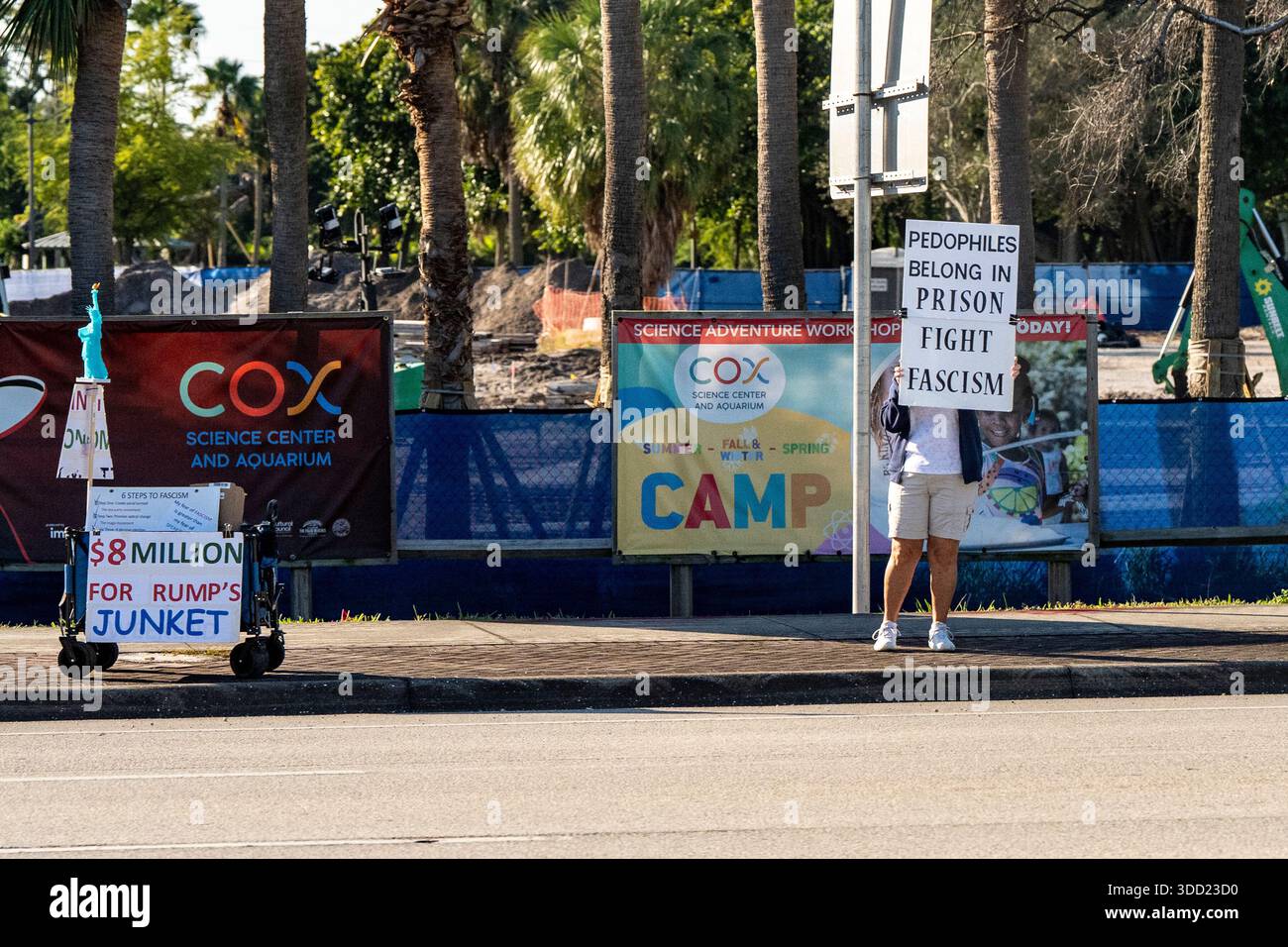 An activist holds a sign as the motorcade for President Donald Trump ...