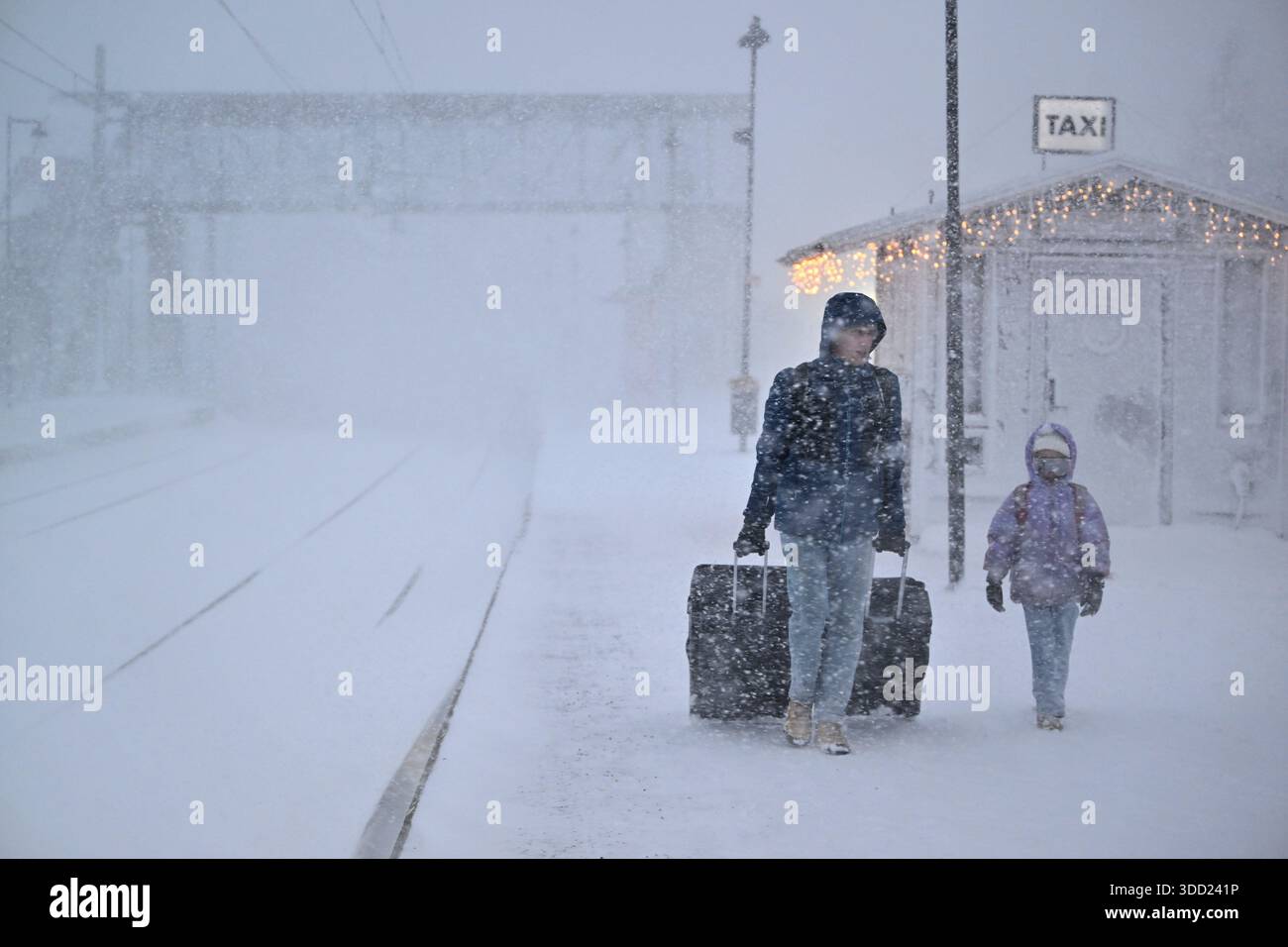 People walk under heavy snow as departures are cancelled at the train ...