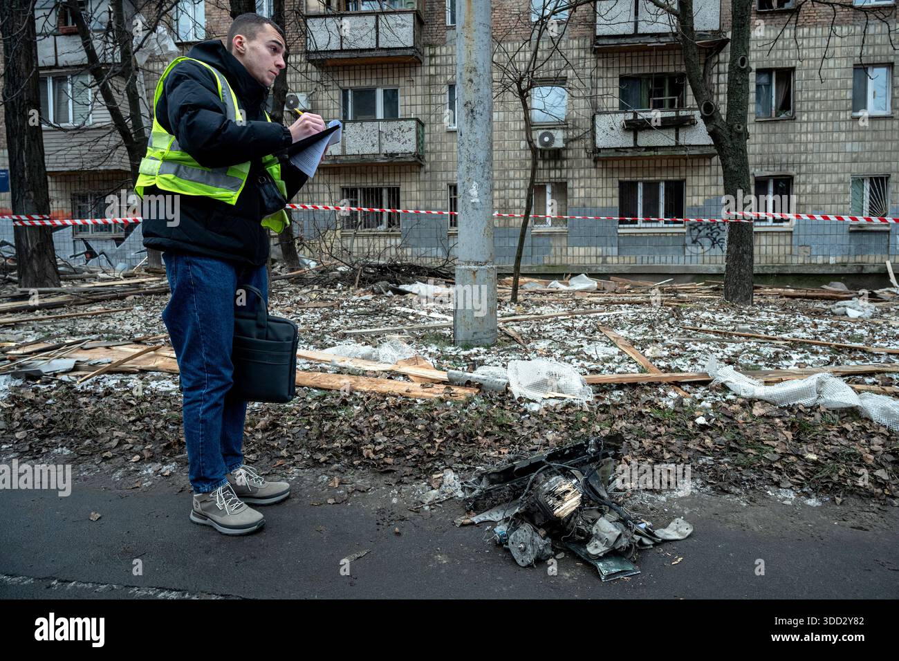 A forensic expert takes notes outside an apartment block in the ...