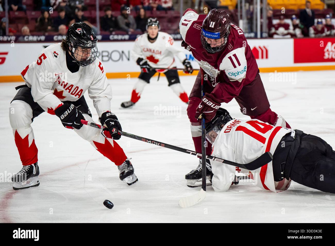 Canada's Ben Danford (14) and Carson Carels (5) defend against Latvia's ...