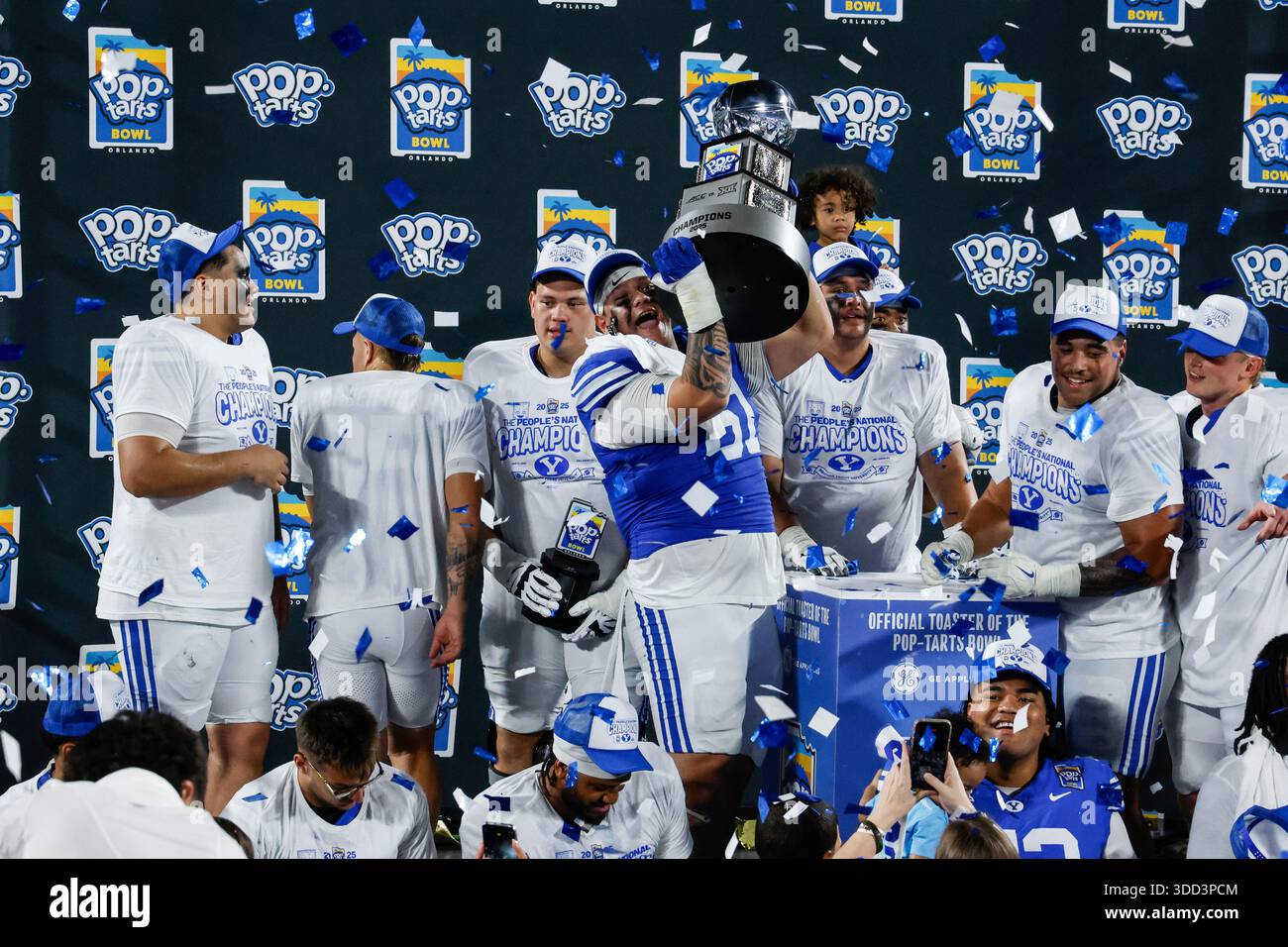BYU offensive lineman Weylin Lapuaho, center, hoists the the trophy ...