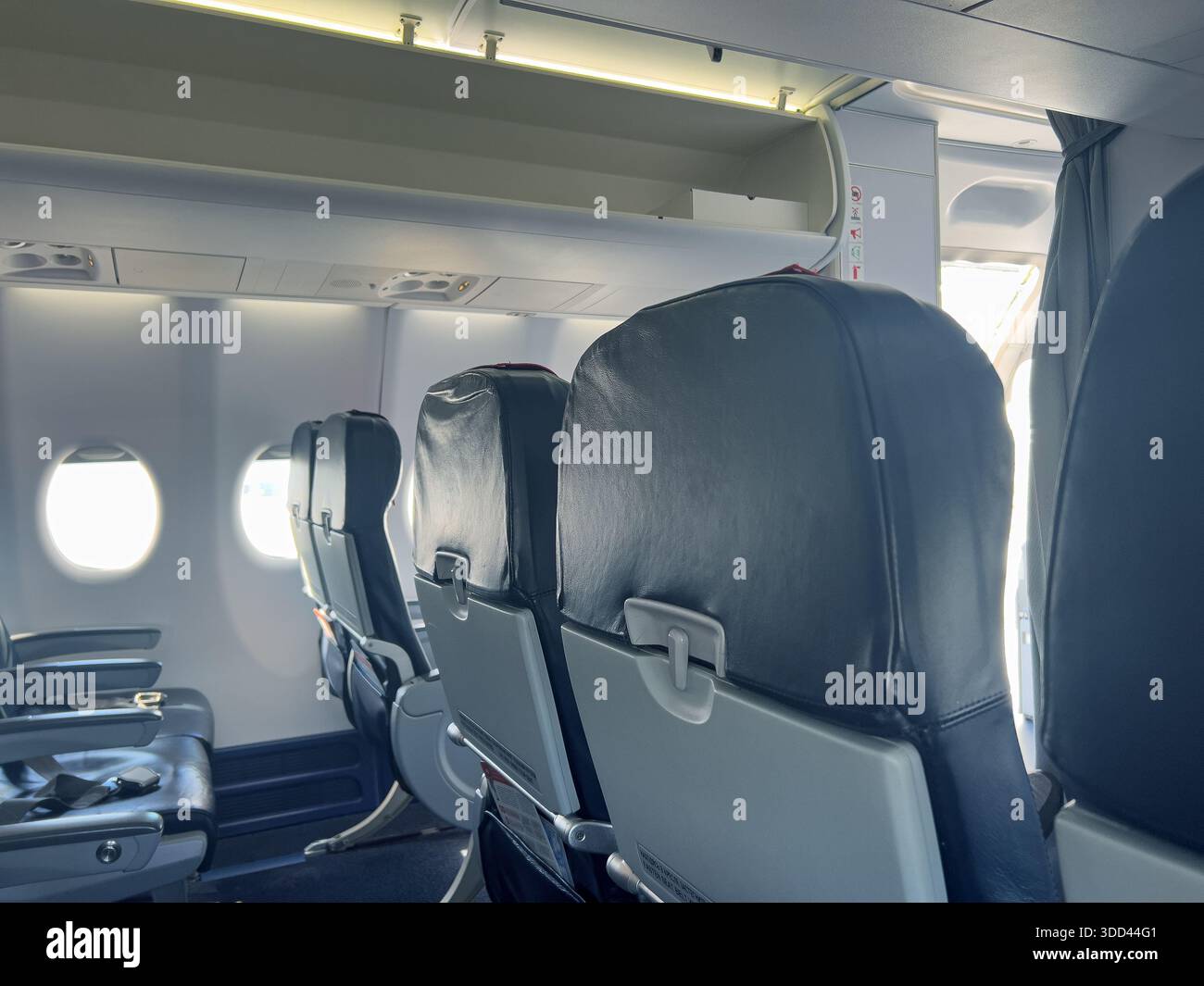 Airplane cabin interior with unoccupied passenger seats, windows, and ...