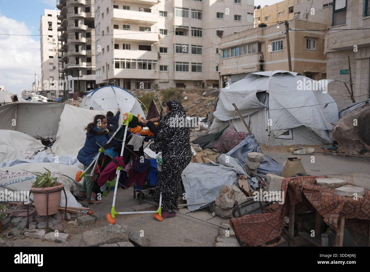 Members of the Al-Ajouri family stand by their tent that was destroyed ...