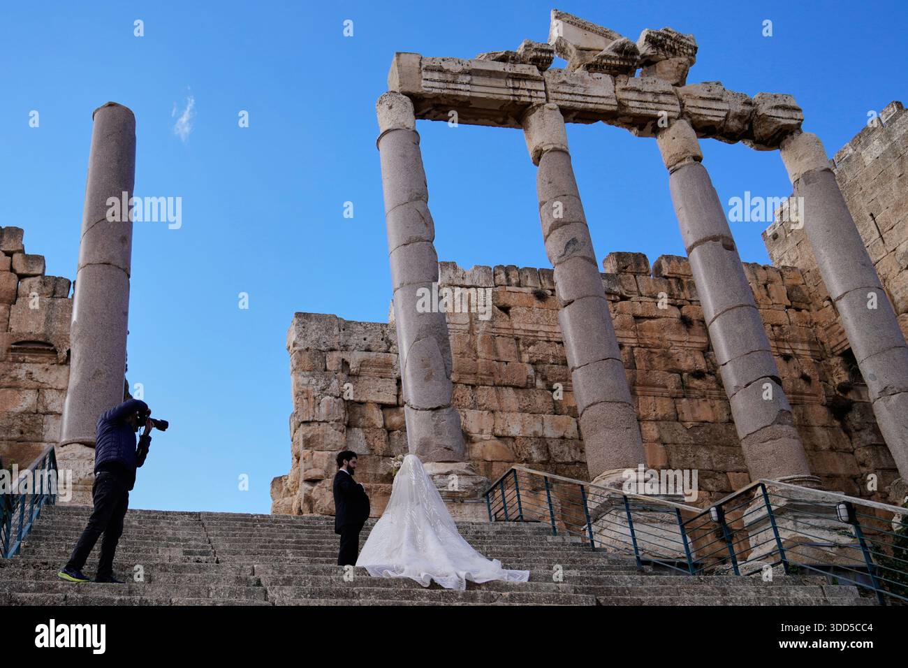 A photographer takes pictures of a bride and groom on the steps of the ...