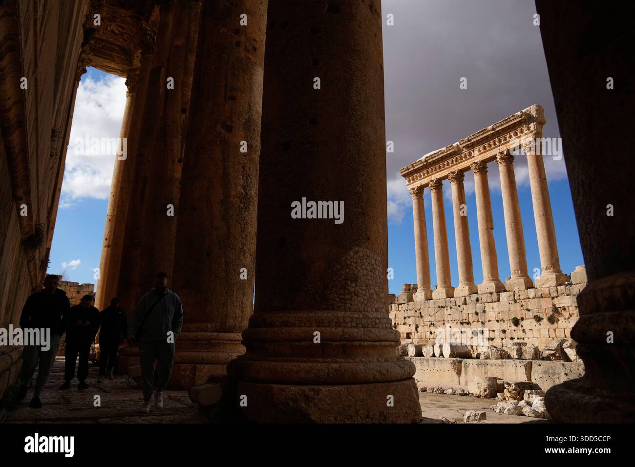 Visitors walk through the Temple of Bacchus as columns of the Temple of ...